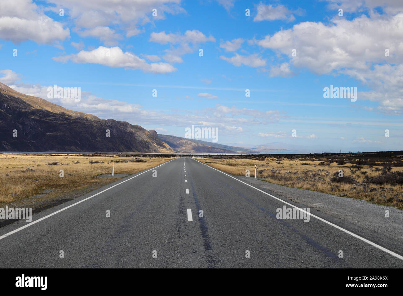 Long and empty road surrounded by mountains Stock Photo - Alamy