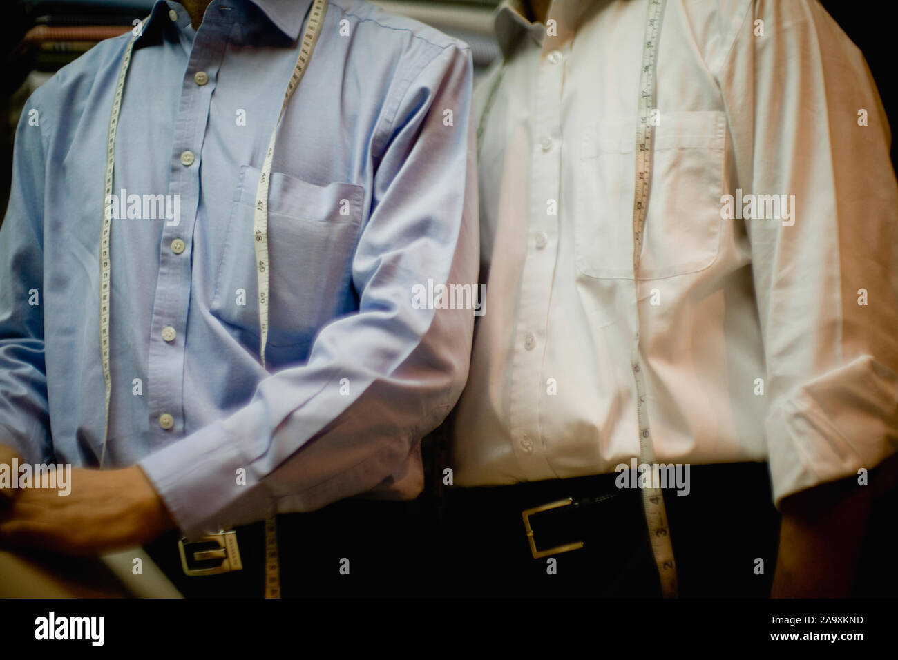 Two men standing next to each other with a tape measure around their ...
