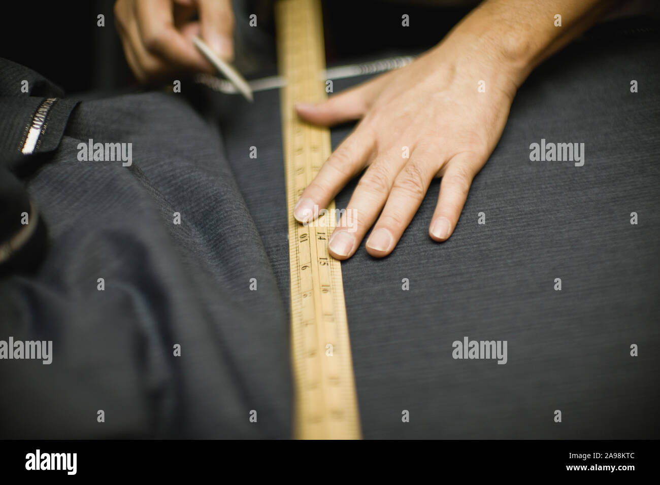 Hand holding a wooden ruler in place on apiece of cloth Stock Photo - Alamy