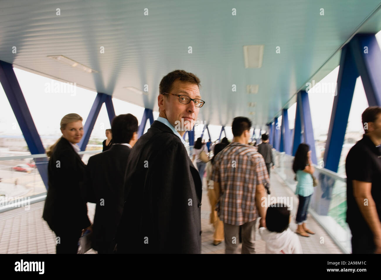 Mid-adult businessman looking over his shoulder while walking in the ...