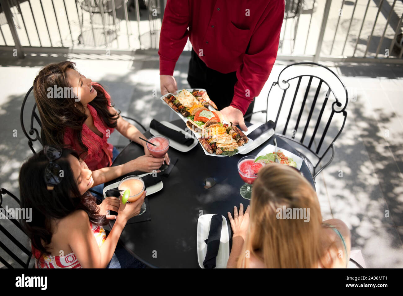 Three smiling friends having lunch at a restaurant Stock Photo - Alamy