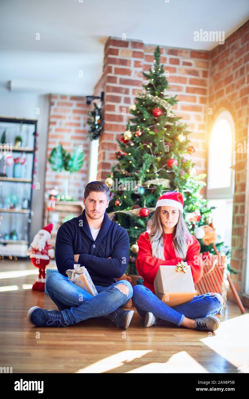 Young couple wearing santa claus hat sitting on the floor around ...