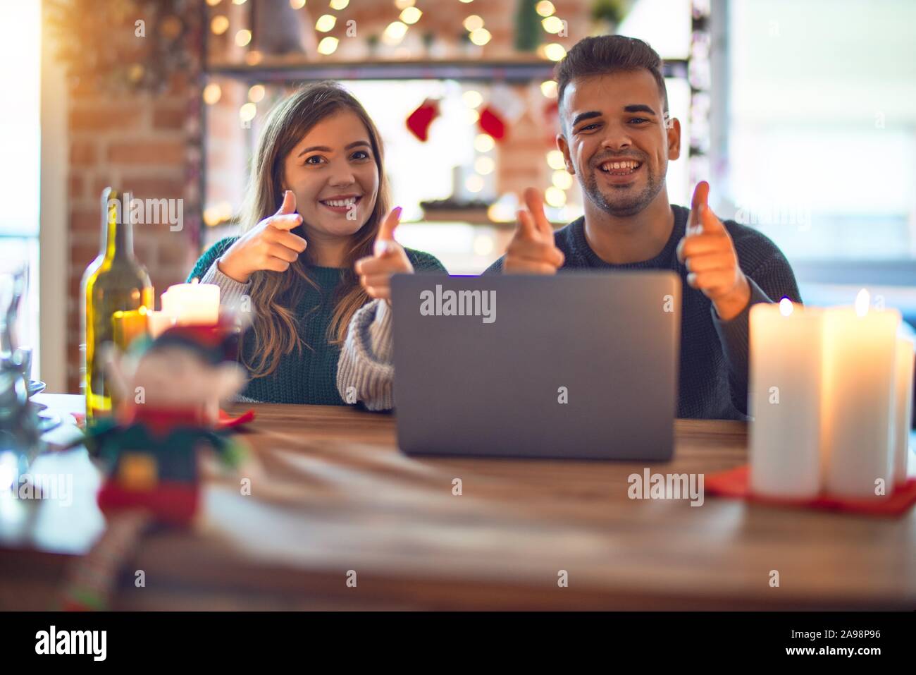 Young beautiful couple sitting using laptop around christmas decoration ...