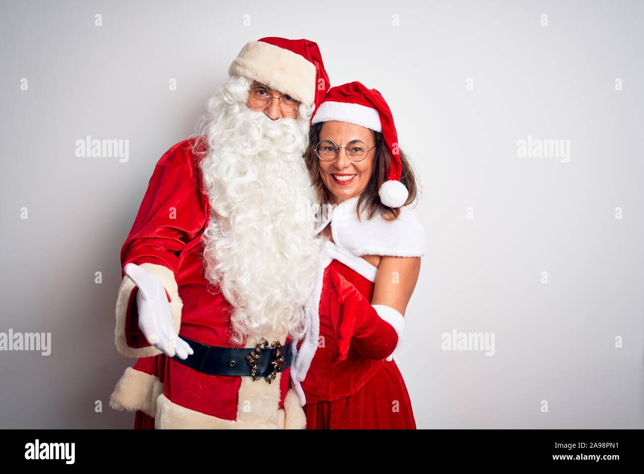 Middle age couple wearing Santa costume hugging over isolated white ...