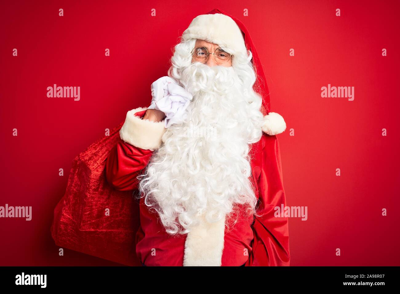 Middle age man wearing Santa costume holding sack with gifts over ...