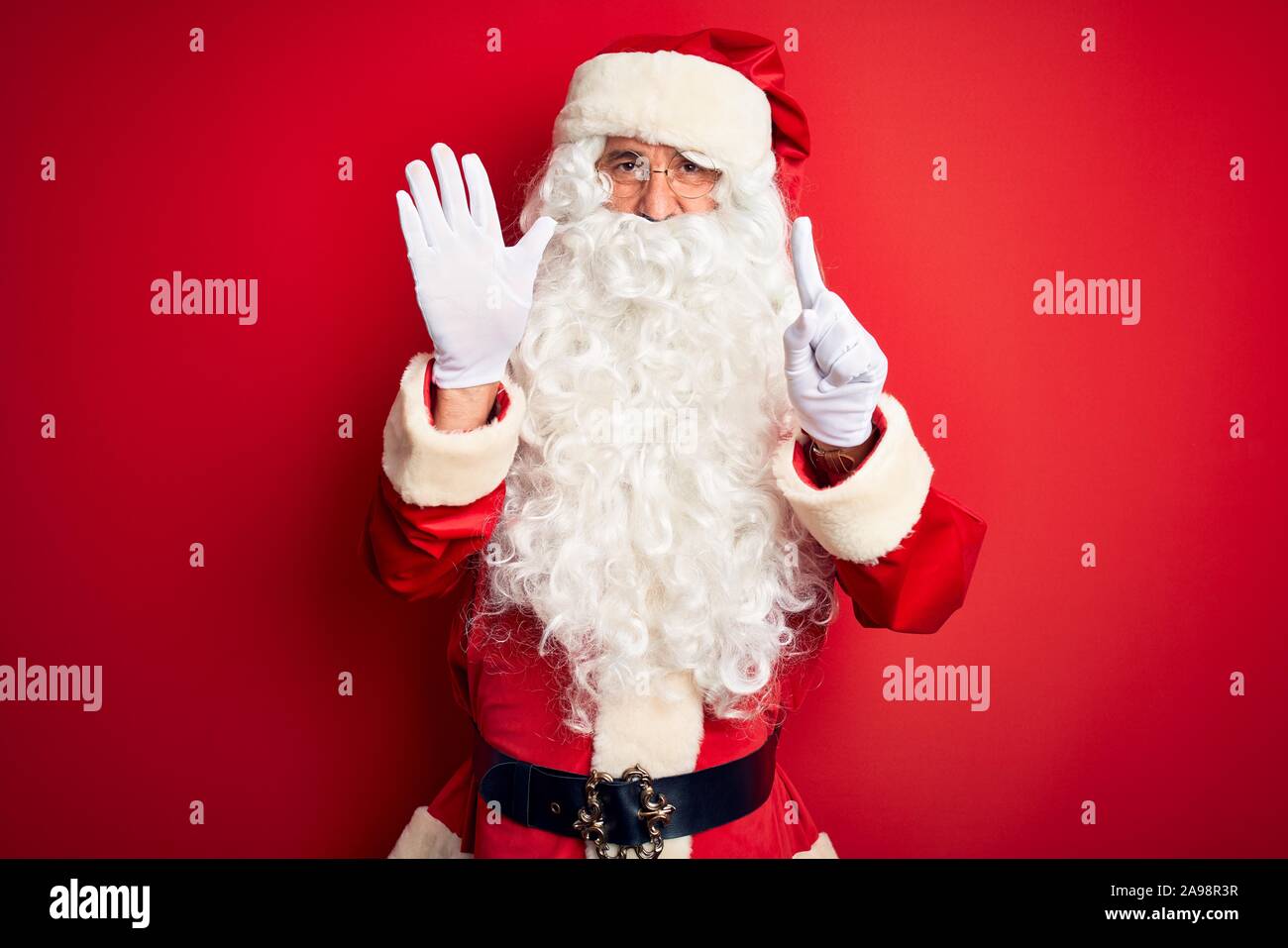 Middle age handsome man wearing Santa costume standing over isolated ...