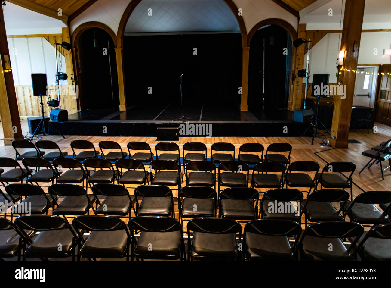 Behind view of concert hall room with empty stage and empty chairs ...