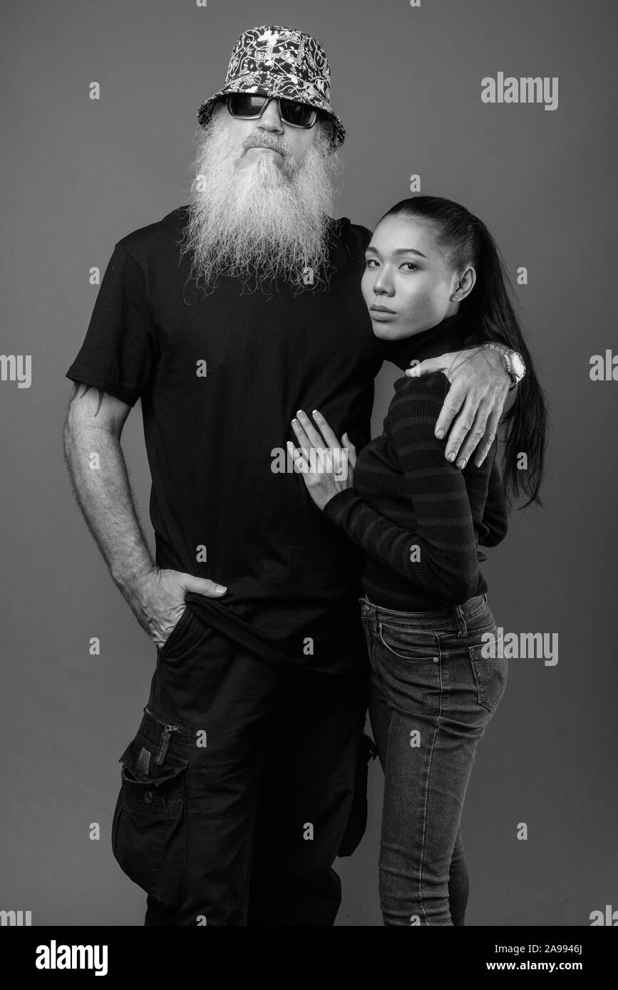 Mature bearded man with young Asian transgender woman together in black ...