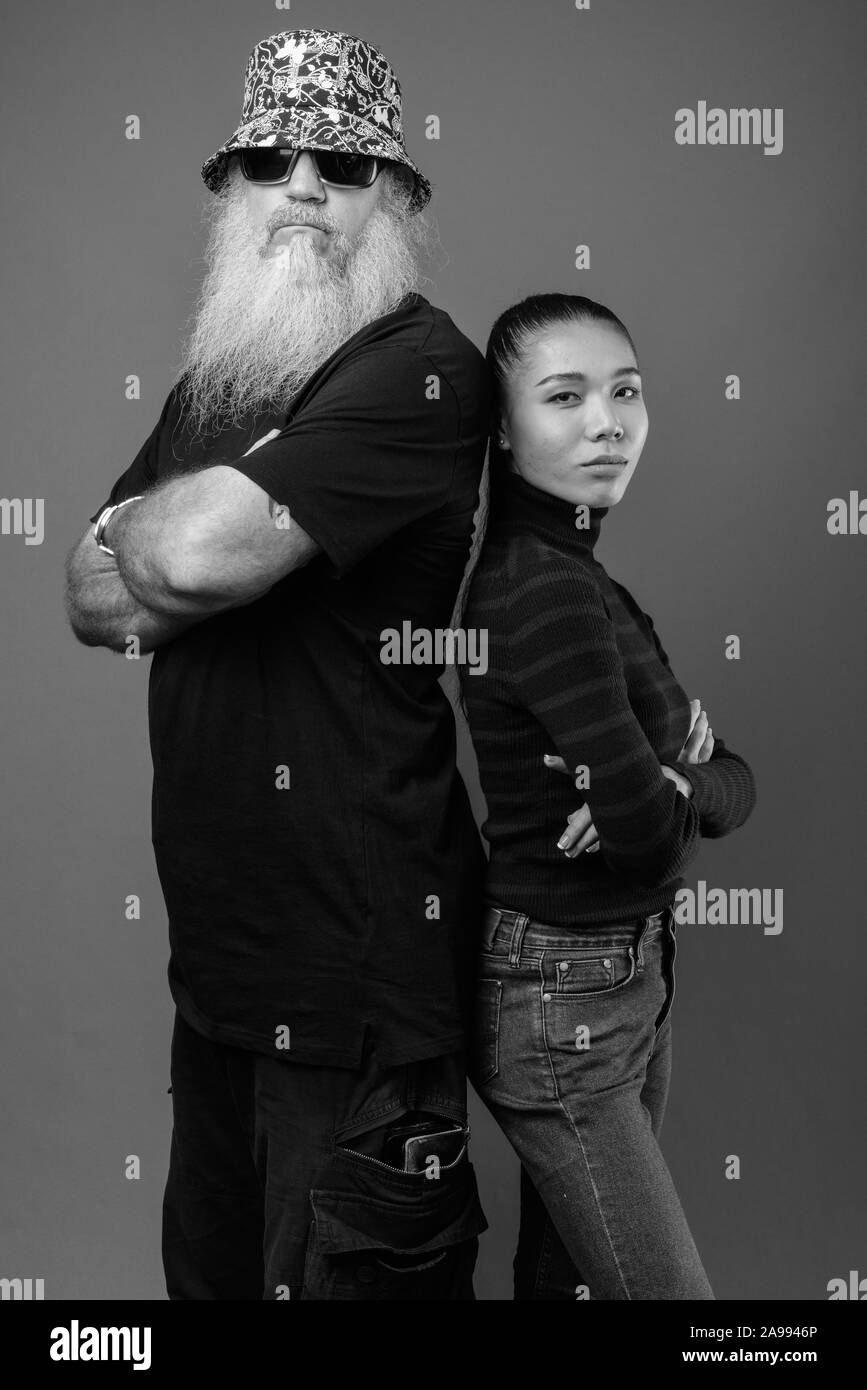 Mature bearded man with young Asian transgender woman together in black ...