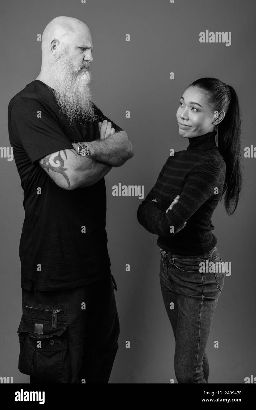 Mature bearded bald man with young Asian transgender woman together in ...