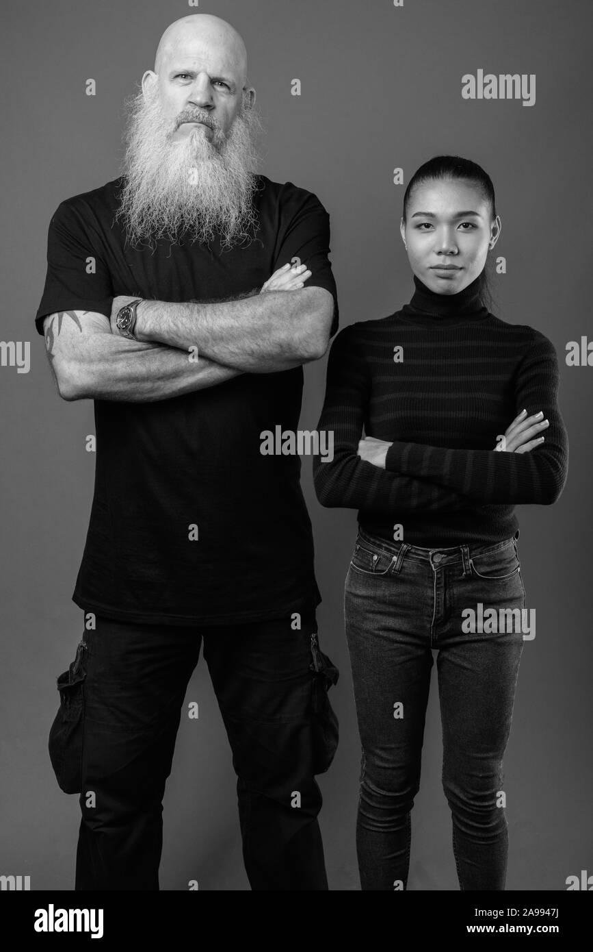 Mature bearded bald man with young Asian transgender woman together in ...