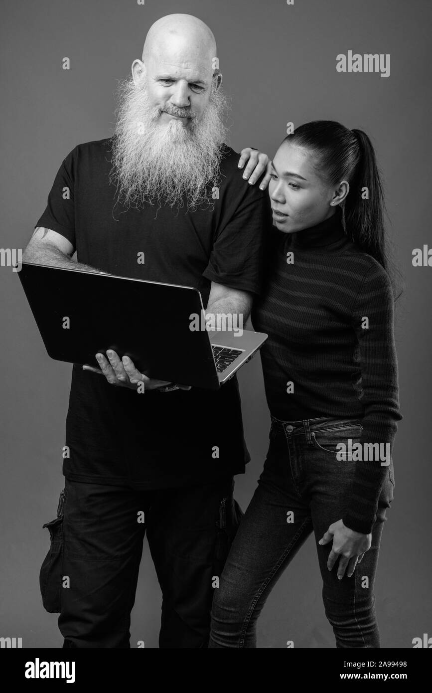 Mature bearded bald man with young Asian transgender woman together in ...