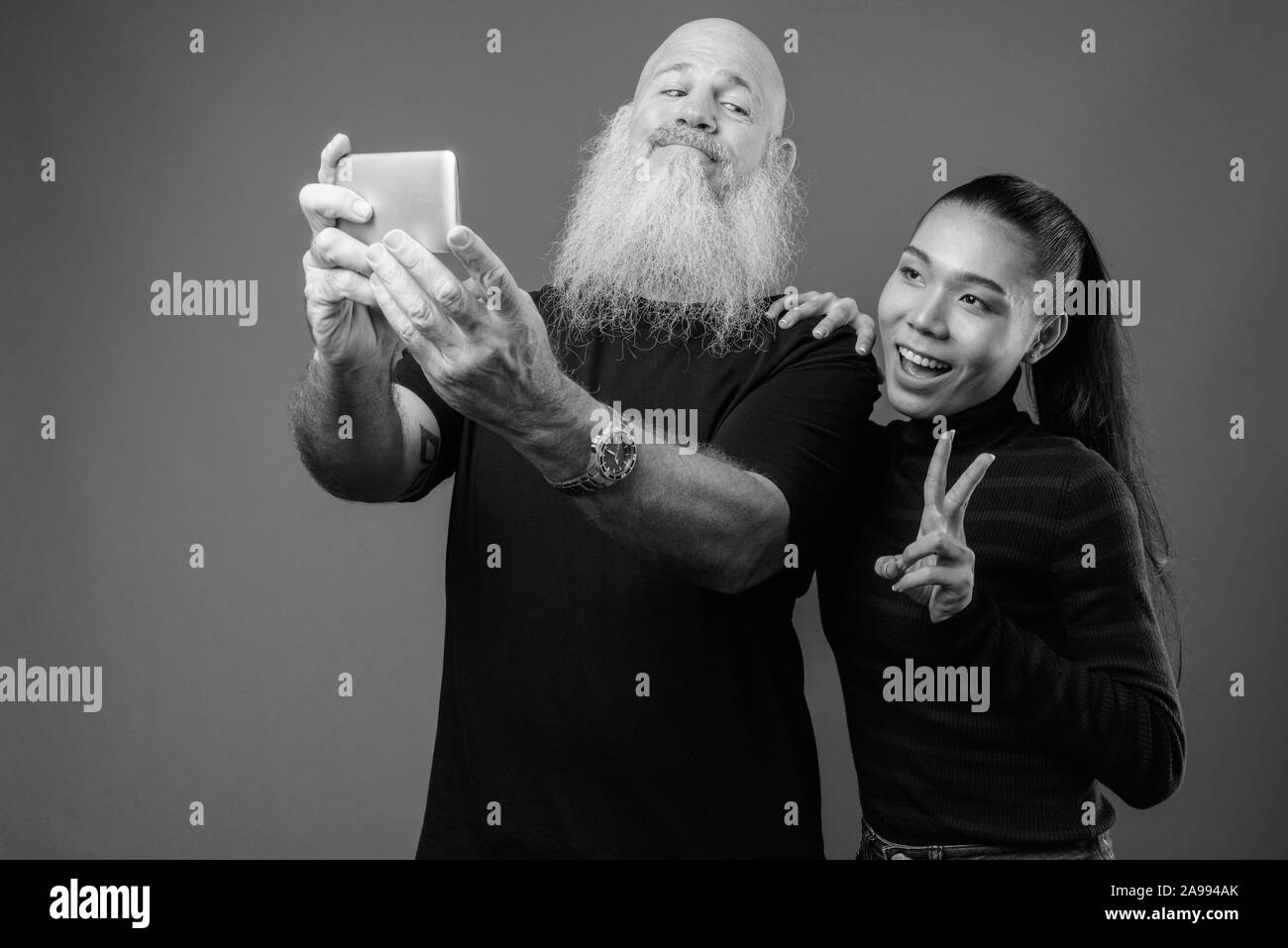 Mature bearded bald man with young Asian transgender woman together in ...