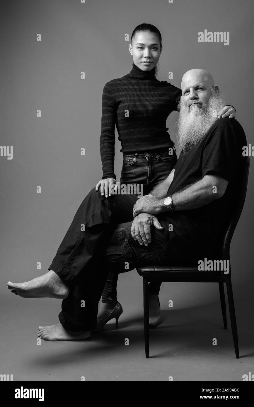 Mature bearded bald man with young Asian transgender woman together in ...