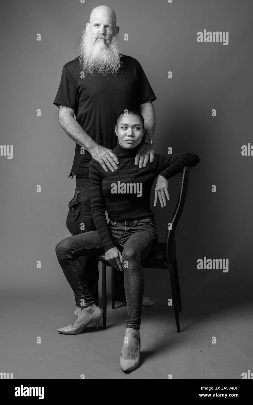 Mature bearded bald man with young Asian transgender woman together in ...