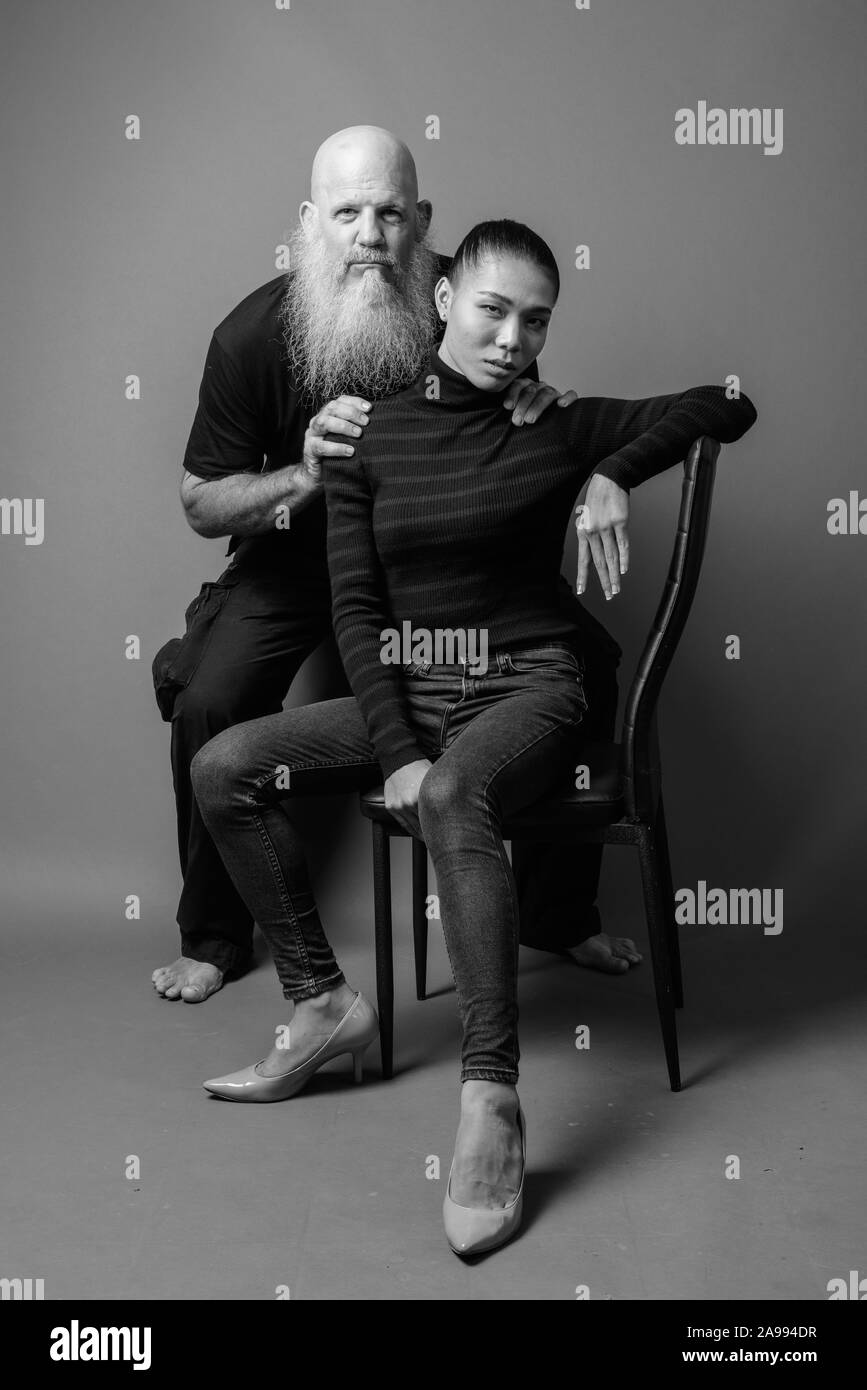 Mature bearded bald man with young Asian transgender woman together in ...