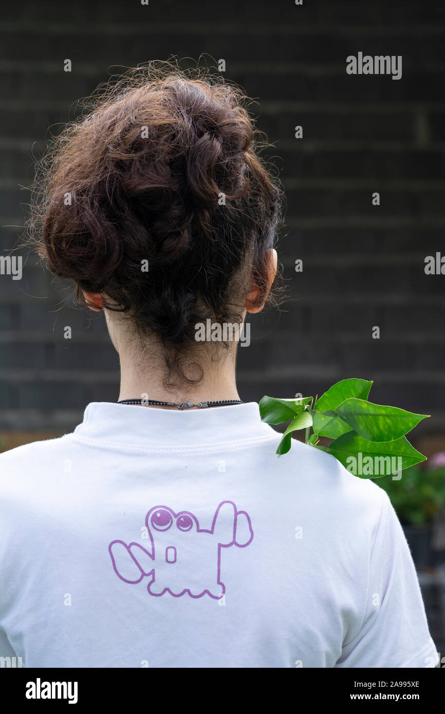 Teenage girl backward looking away and holding a green leaves branch ...