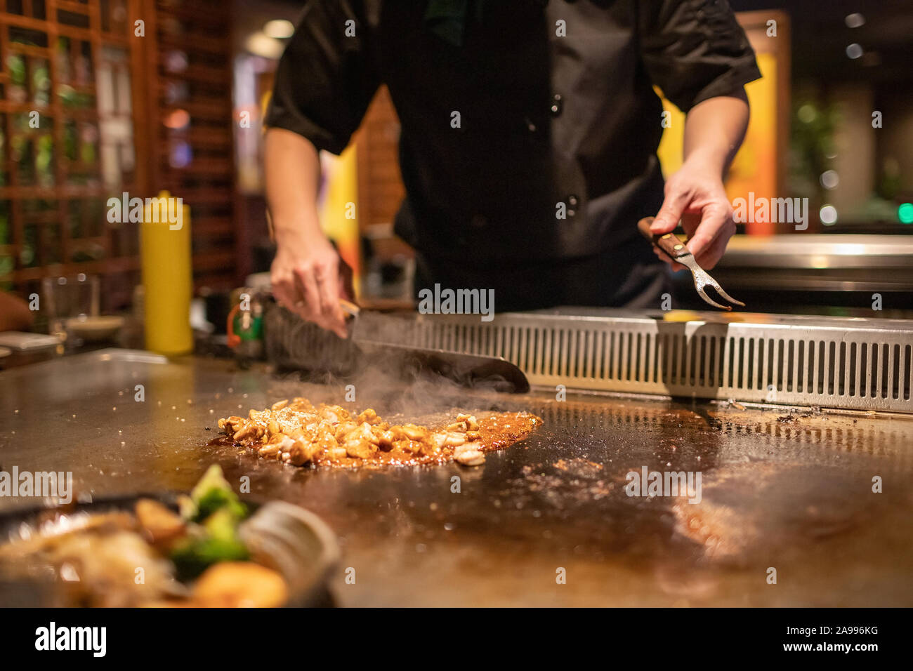 Teppanyaki chef cooking Japanese Teriyaki Chicken on hot metal plate ...