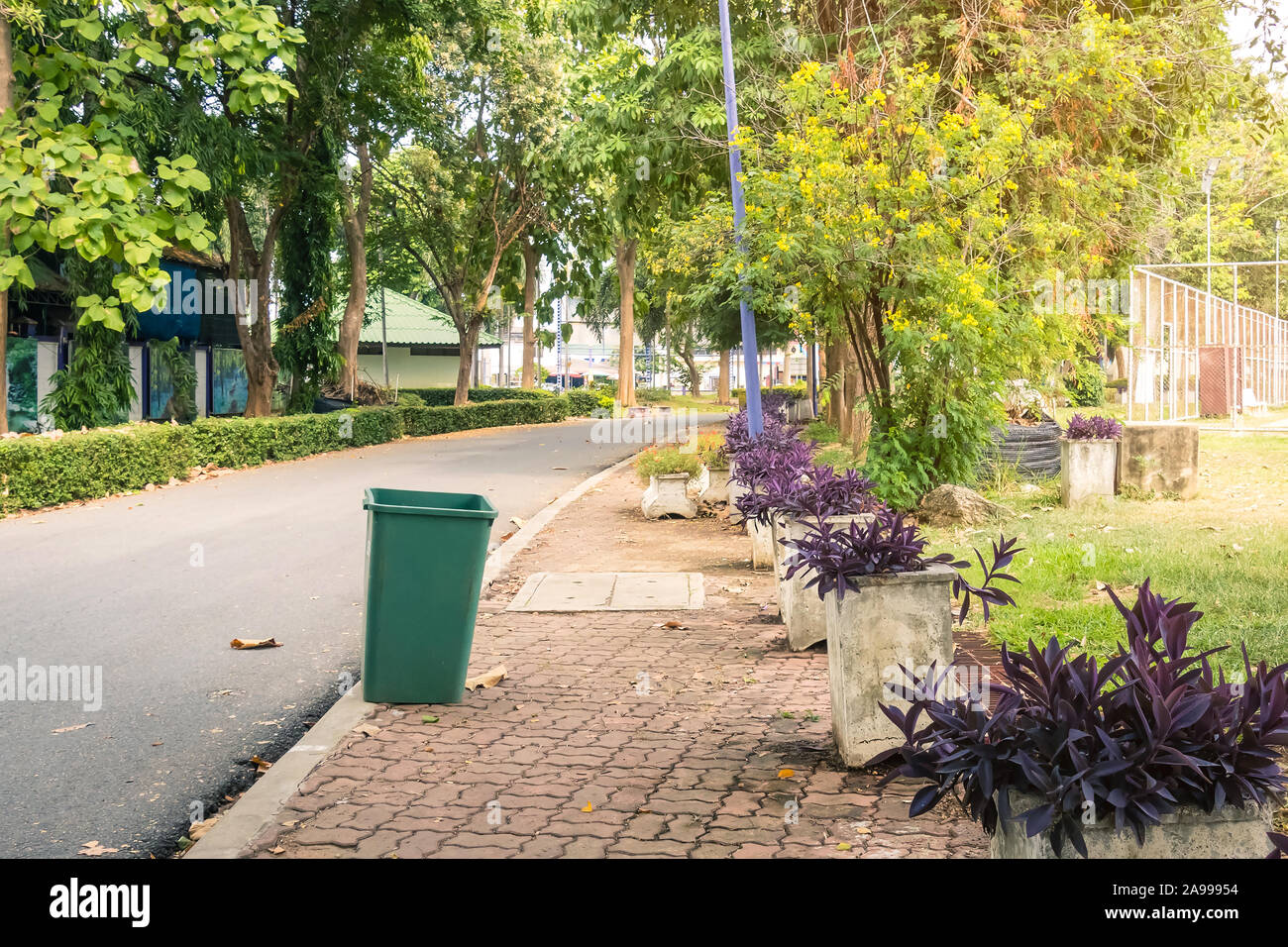 An old green dustbin in the public park beside the walk way for protect ...
