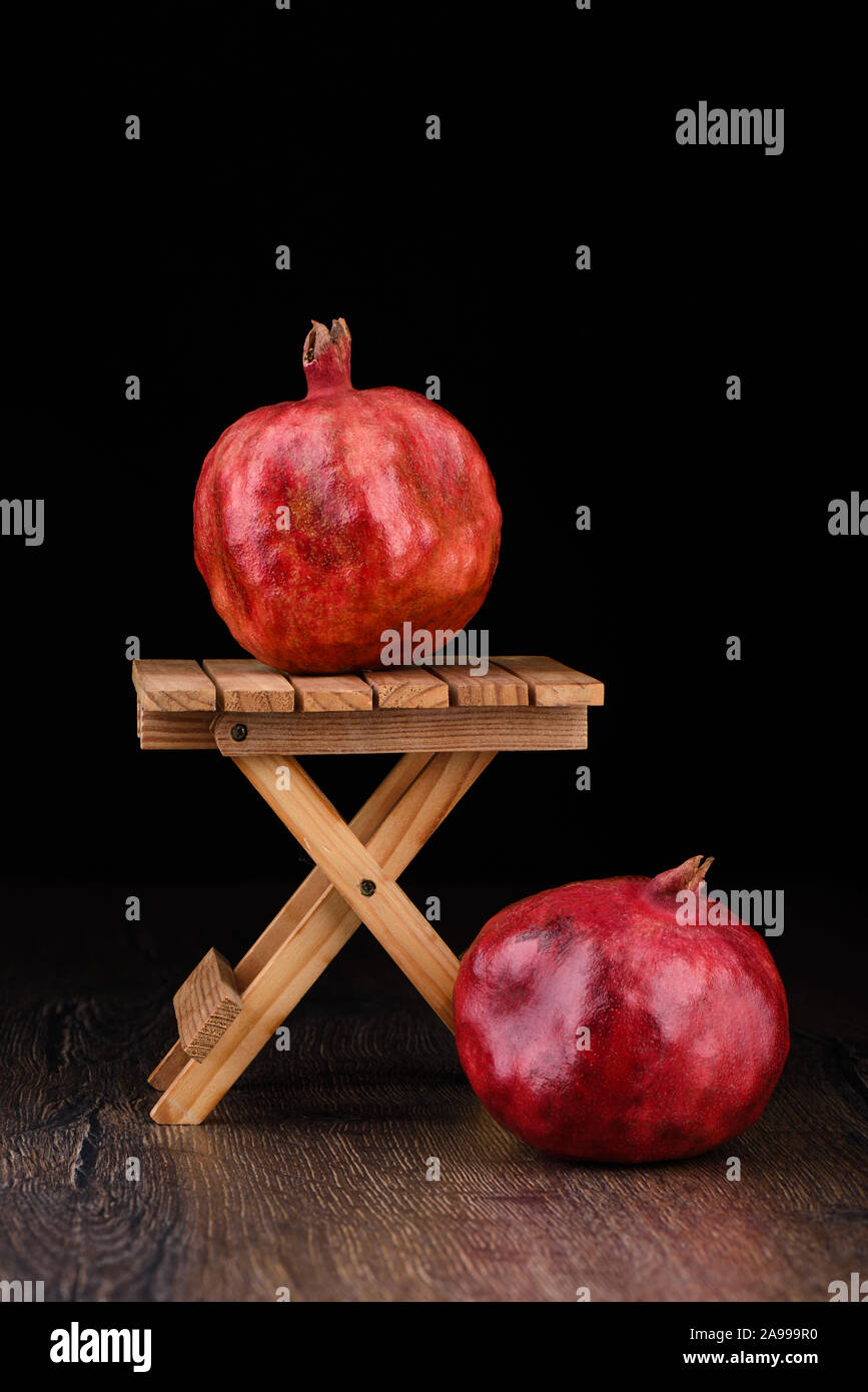 Two ripe pomegranates. Pomegranate on a wooden stand and pomegranate on ...