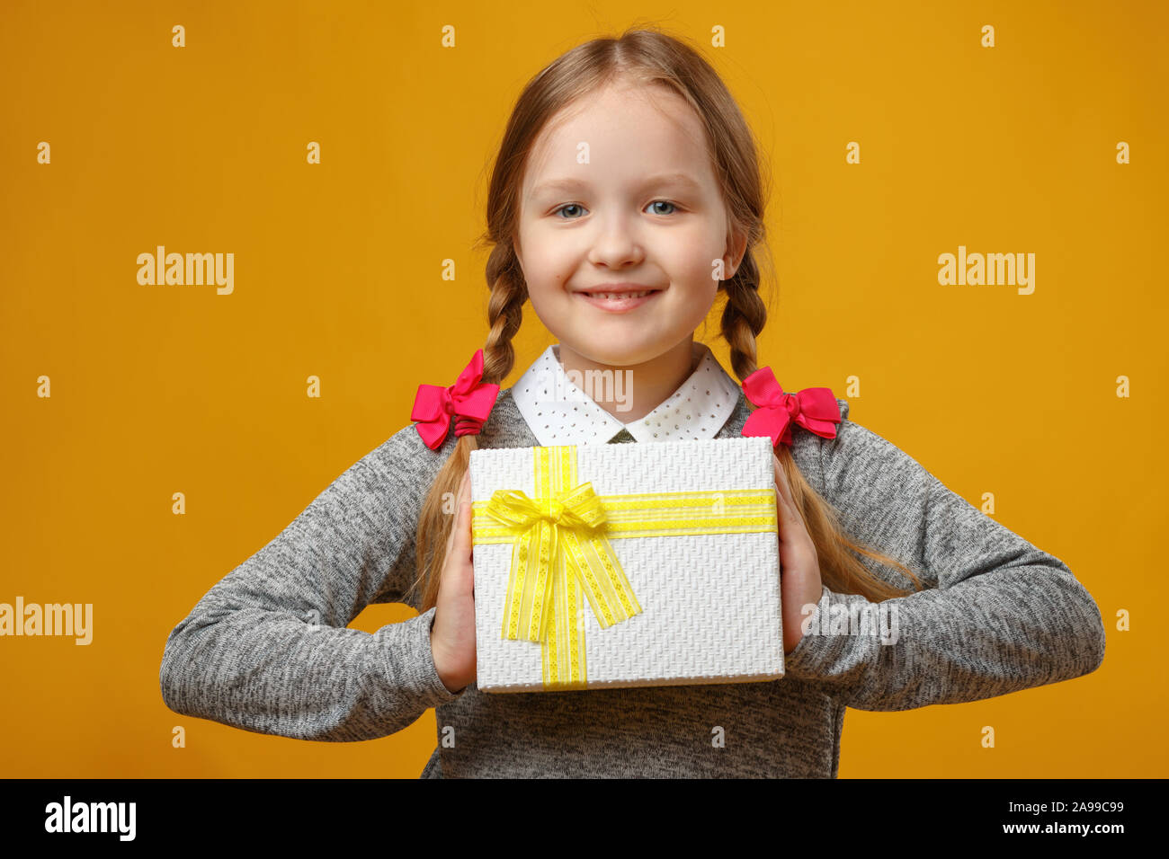 Cute little girl holding a box with a gift in her hands. Baby with ...