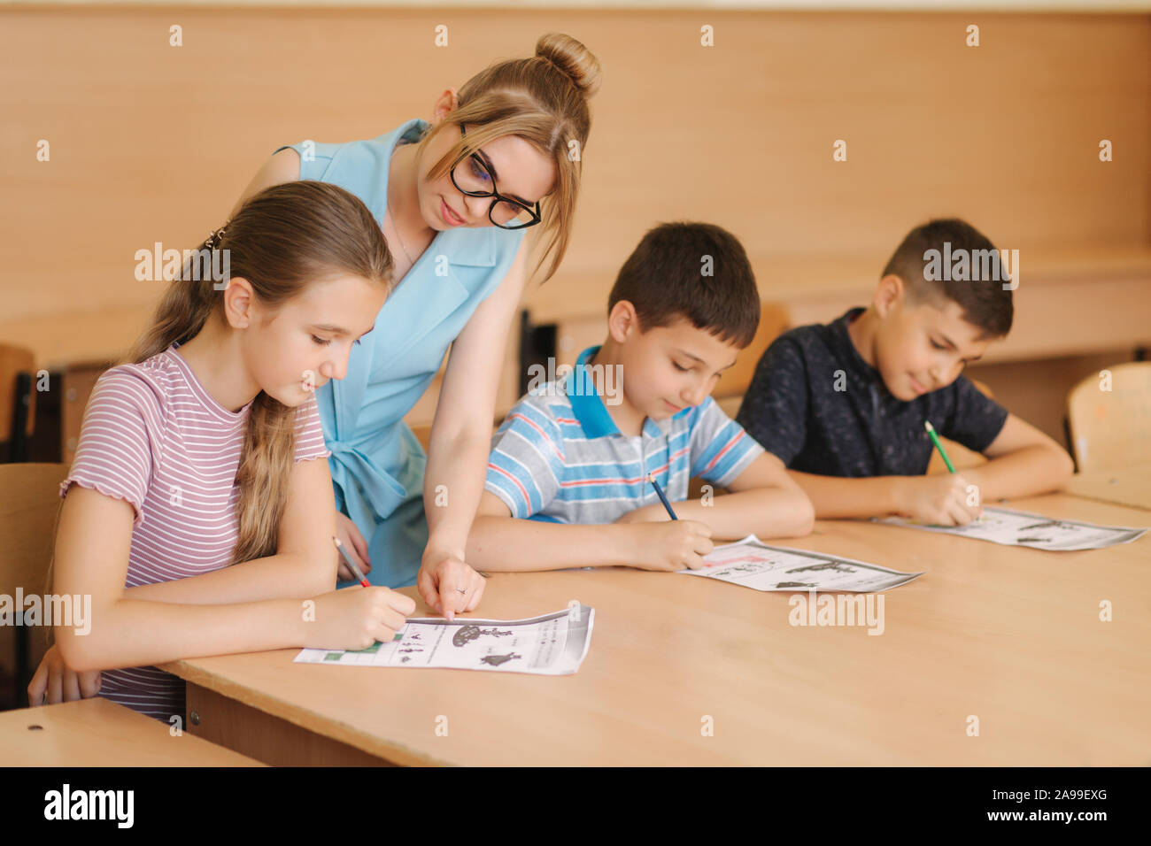 Teacher helping school kids writing test in classroom. education ...