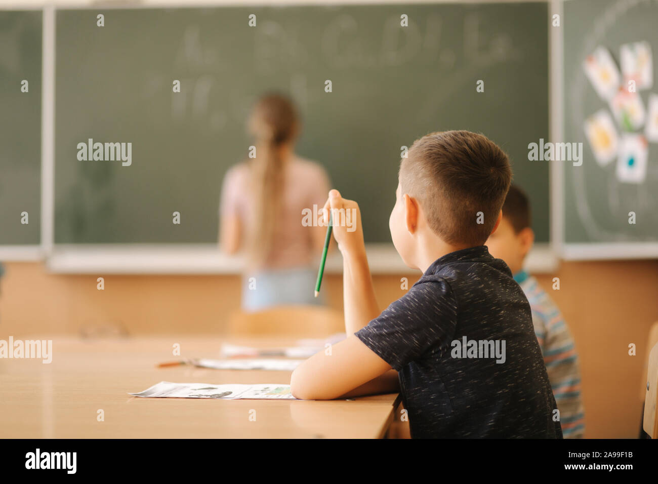 Group of school kids with pens and notebooks writing test in classroom ...