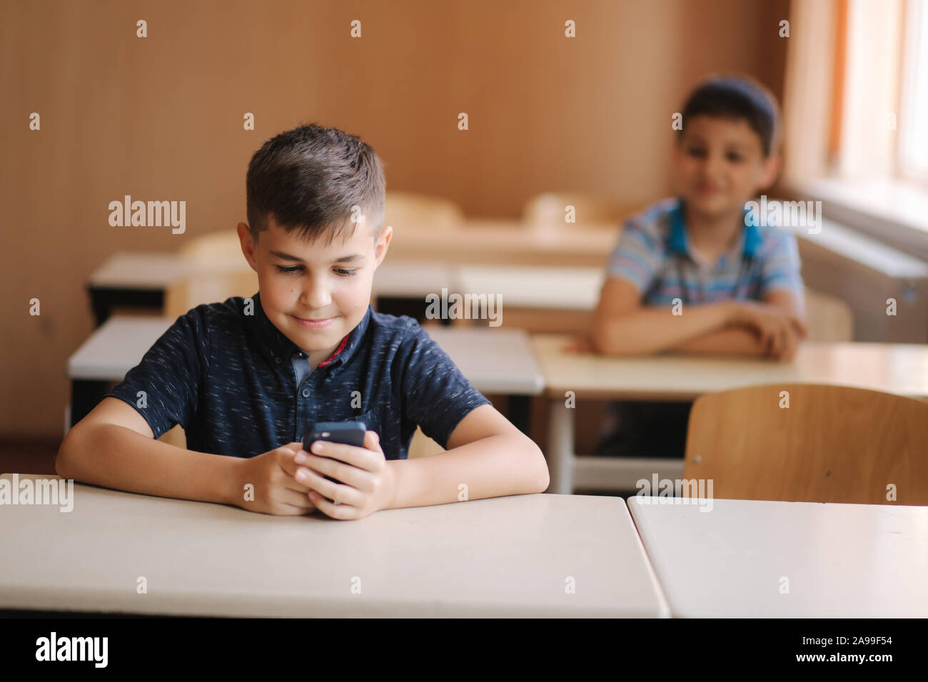 Cute little boy use phone during lesson. Two schollboy in class Stock ...