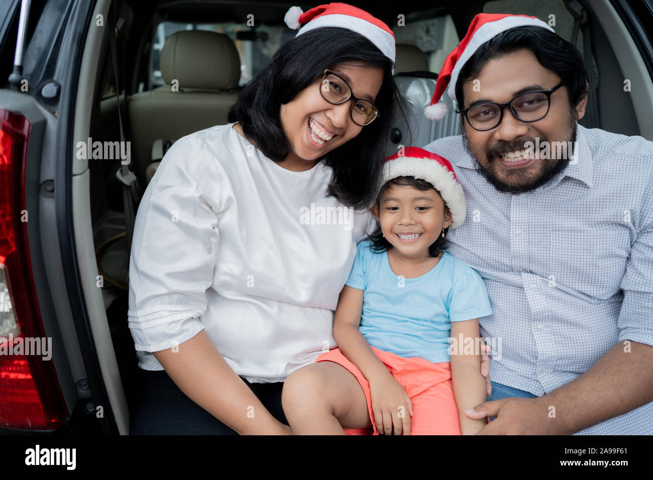 family with suitcase sitting on car trunk Stock Photo - Alamy