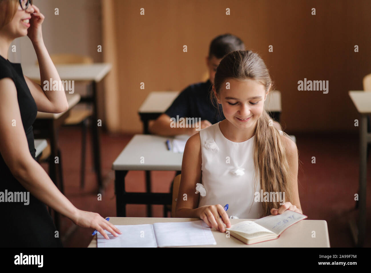 Teacher helping school kids writing test in classroom. education ...