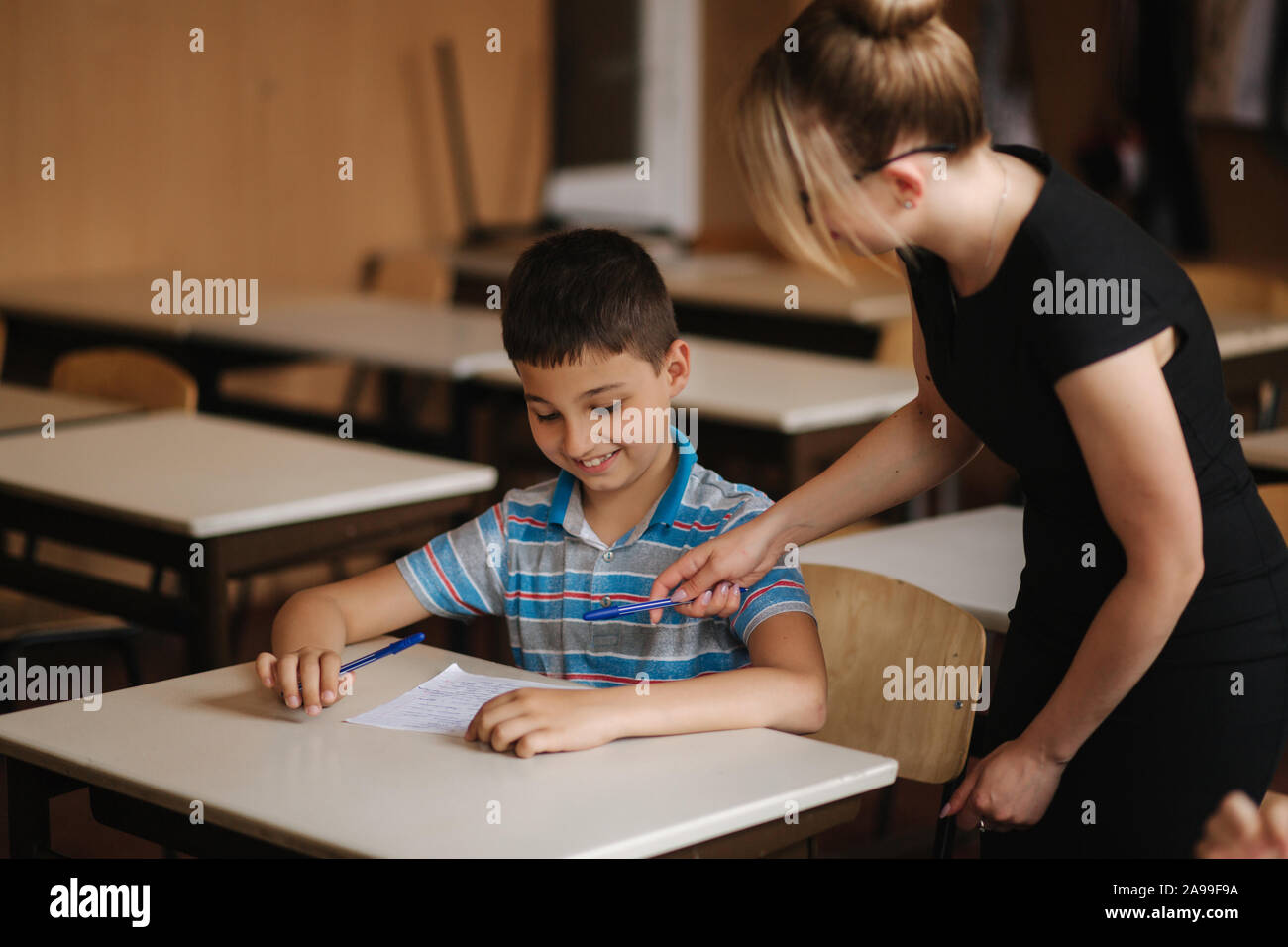 Teacher helping school kids writing test in classroom. education ...