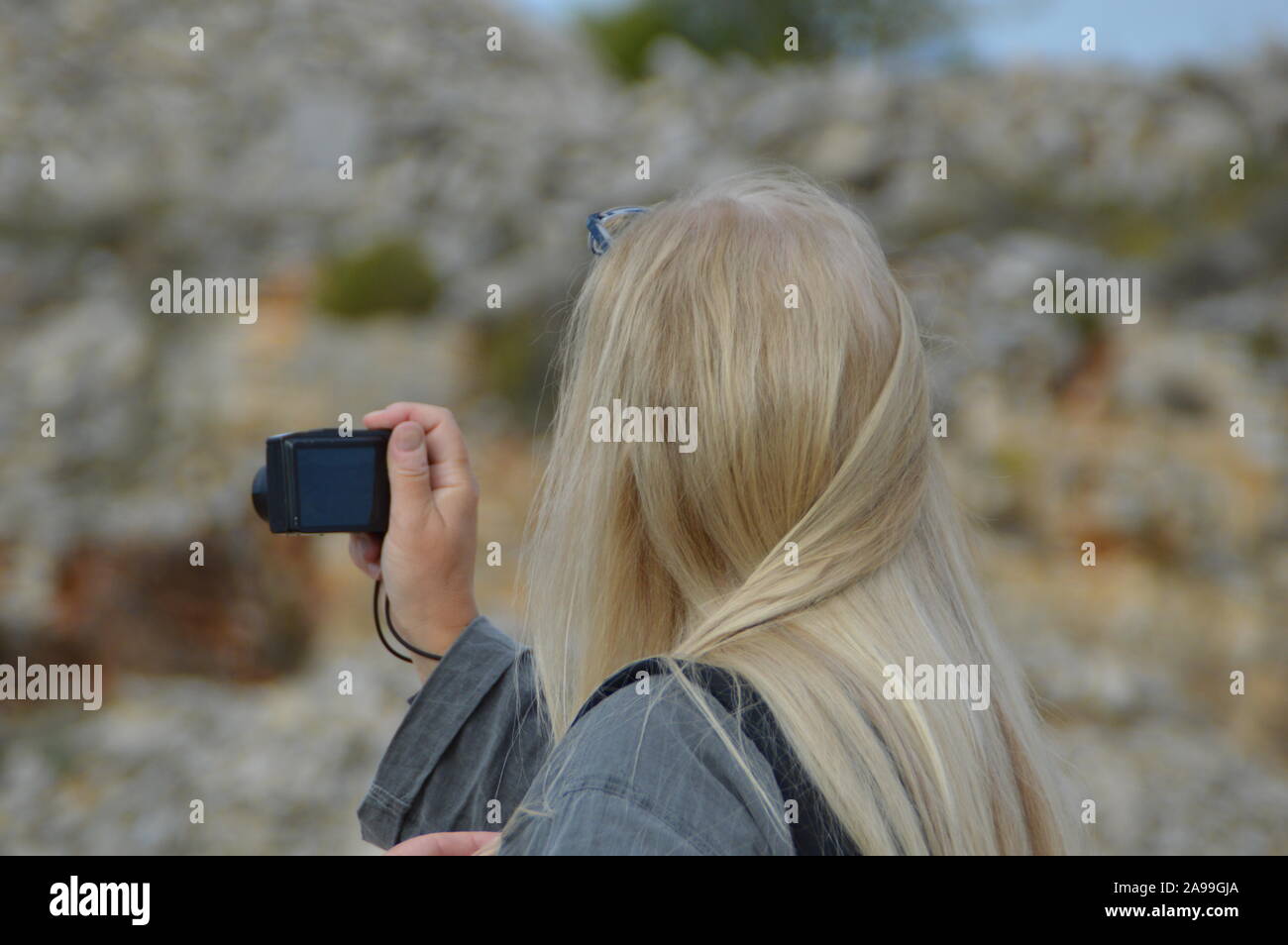 Rear view portrait of the blond woman taking photo in nature Stock ...