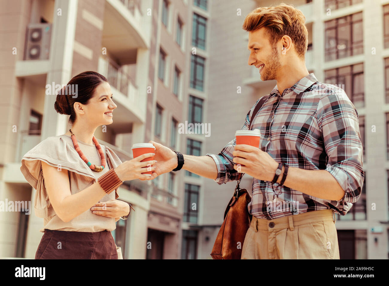 Positive delighted young man giving coffee to his friend Stock Photo ...