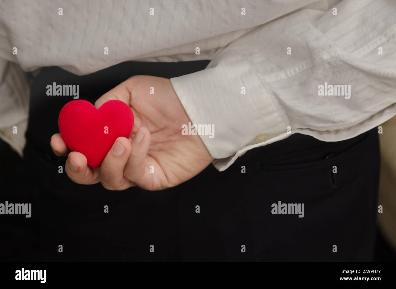 Man holds behind his back in his hand engagement heart shape box. Love ...
