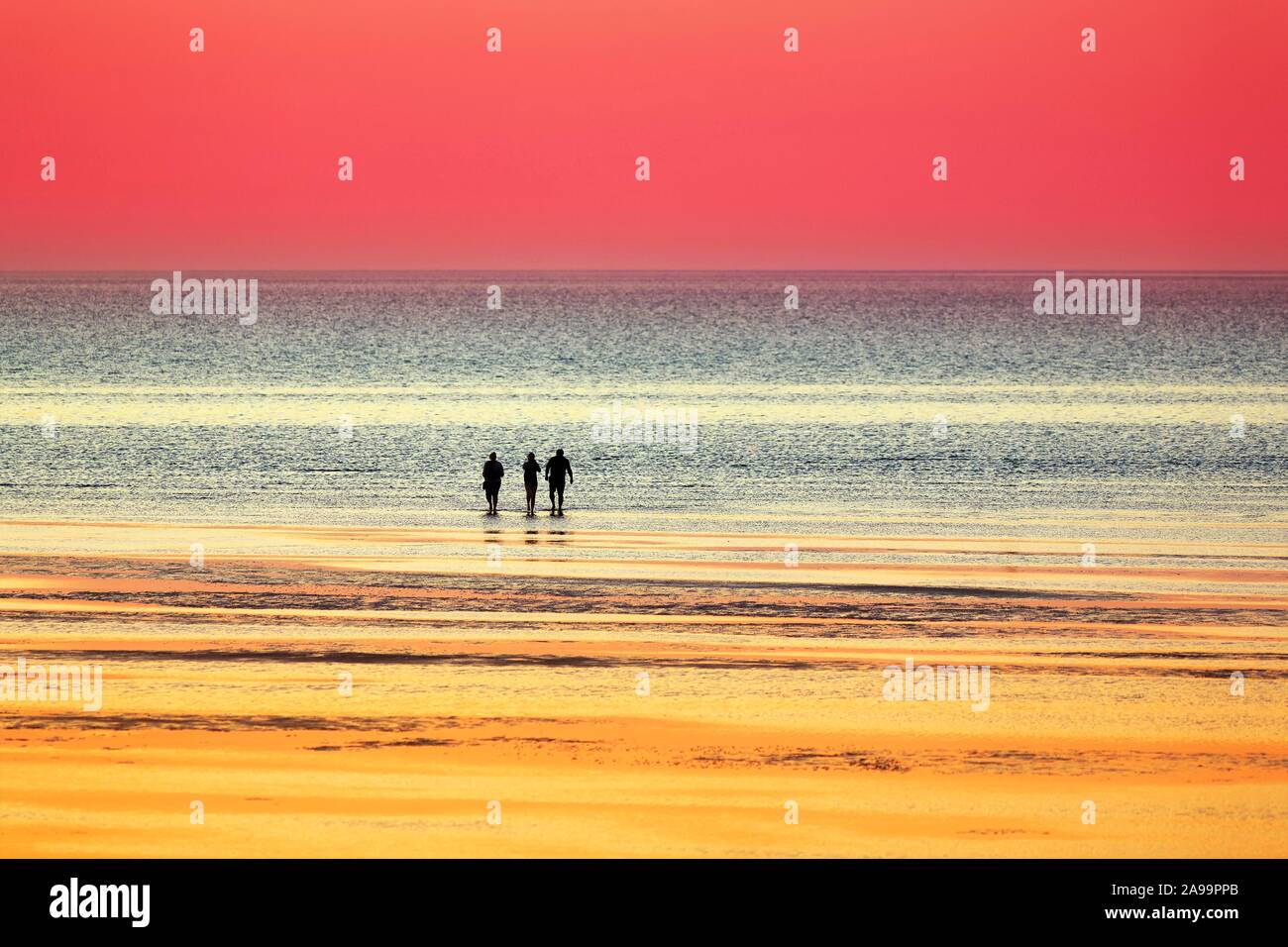 Silhouettes of people on the beach in the water at sunset, North Sea ...