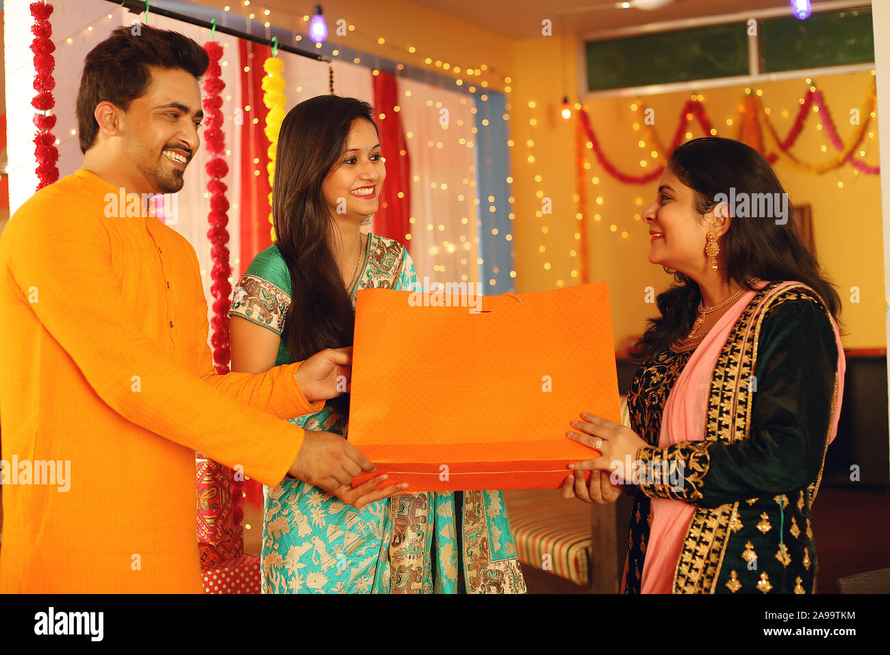 Cute young Indian couple wearing traditional ethnic clothes giving gift ...