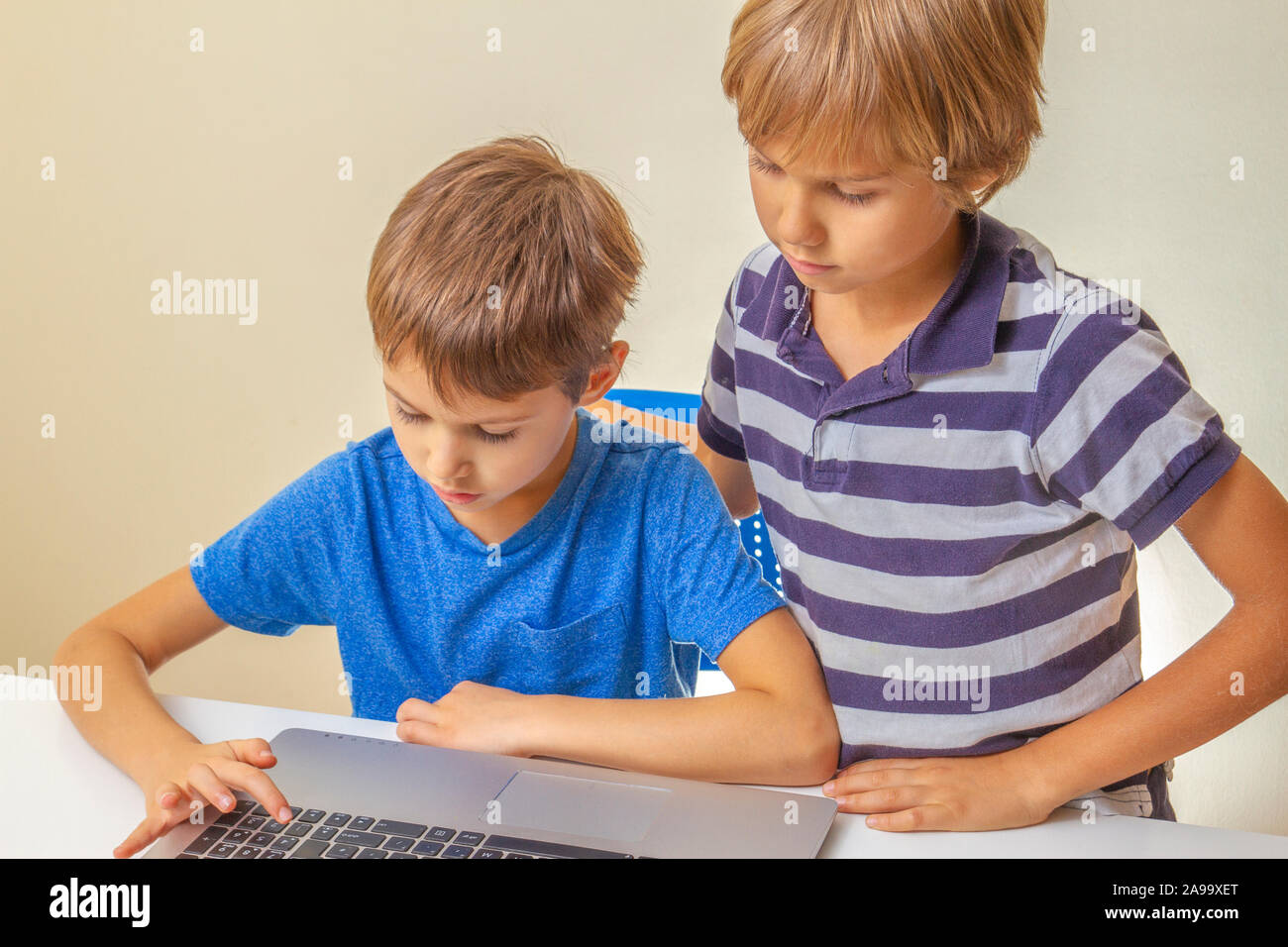 Focused child typing laptop computer and other kid help him. School ...