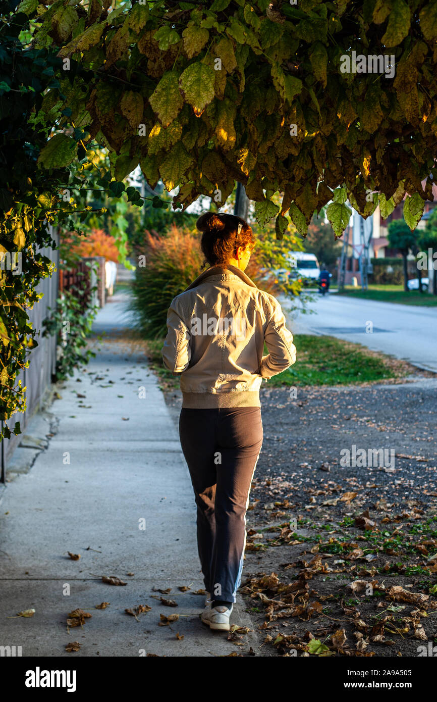 Beautiful woman walking in a walkway in the city during sunset Stock ...