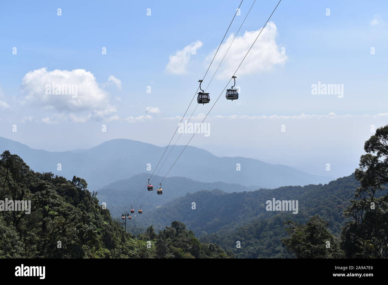 aerial view of two cable cars from far away with mountains, greenery ...