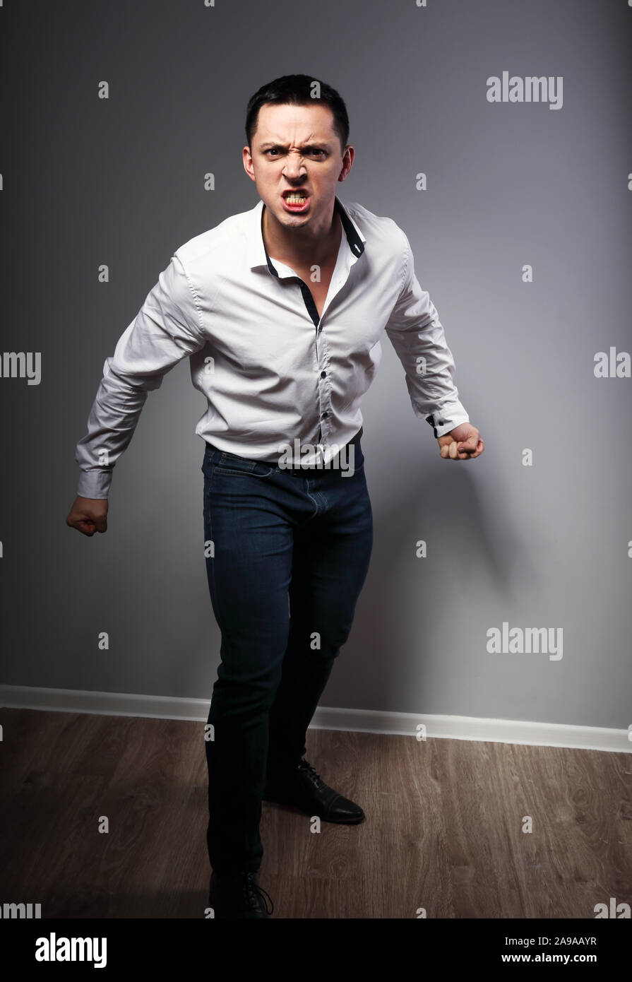 Angry young business man grimacing with aggressive eyes and holding ...