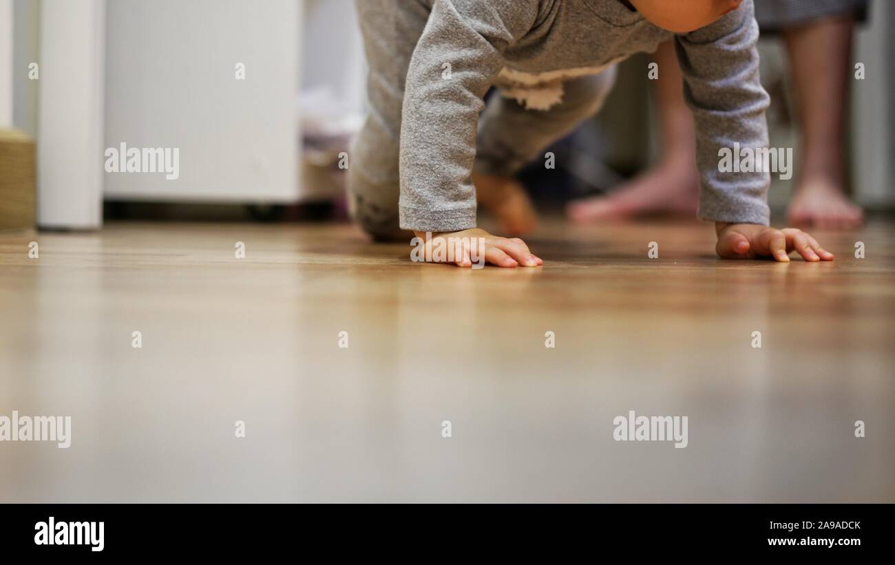 toddler crawling on clean bedroom wooden floor while mother watching in ...