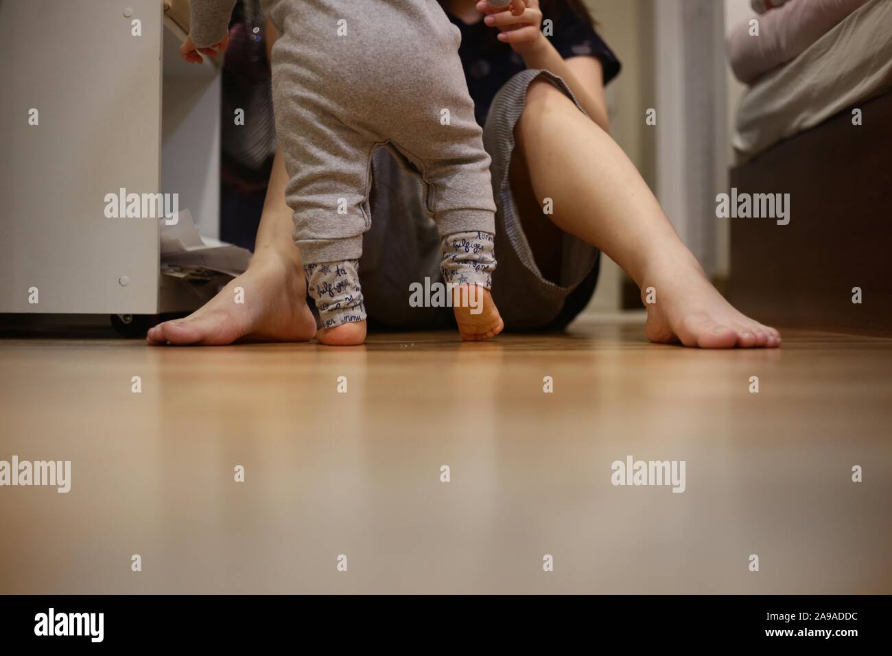 baby walking towards mother. small kid walk on bedroom wooden floor ...