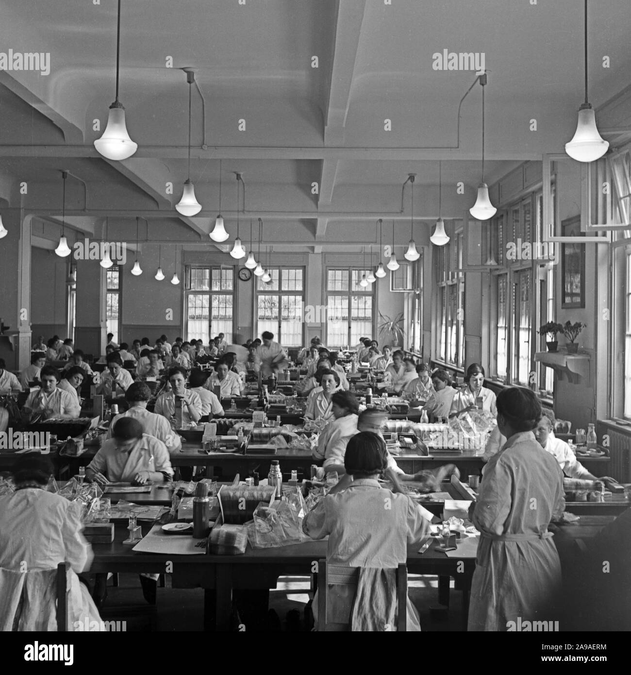 Women at a factory hall packing cellophane packages, Germany 1930s ...