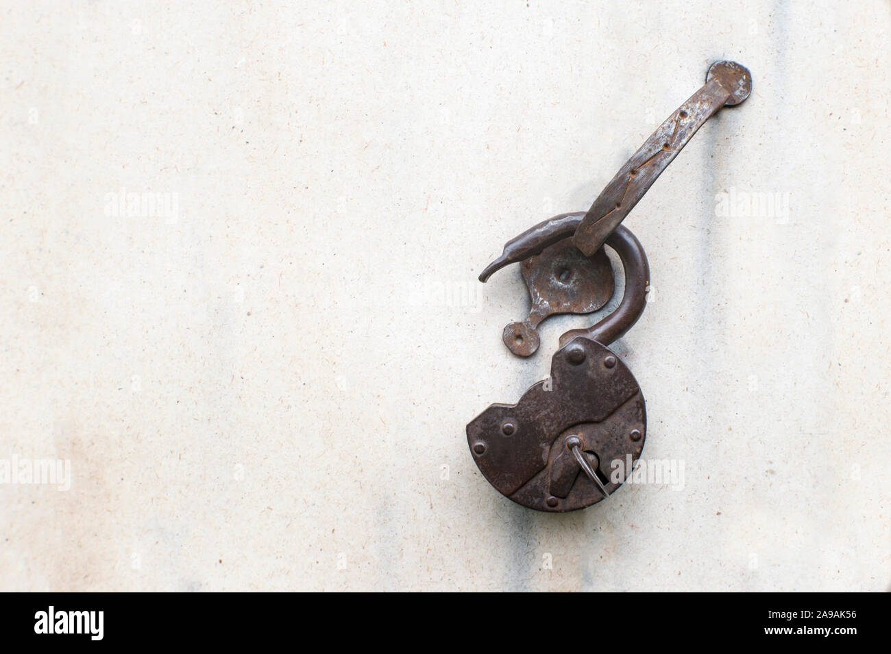 A vintage open wrought iron lock with an inserted key hangs on a ...