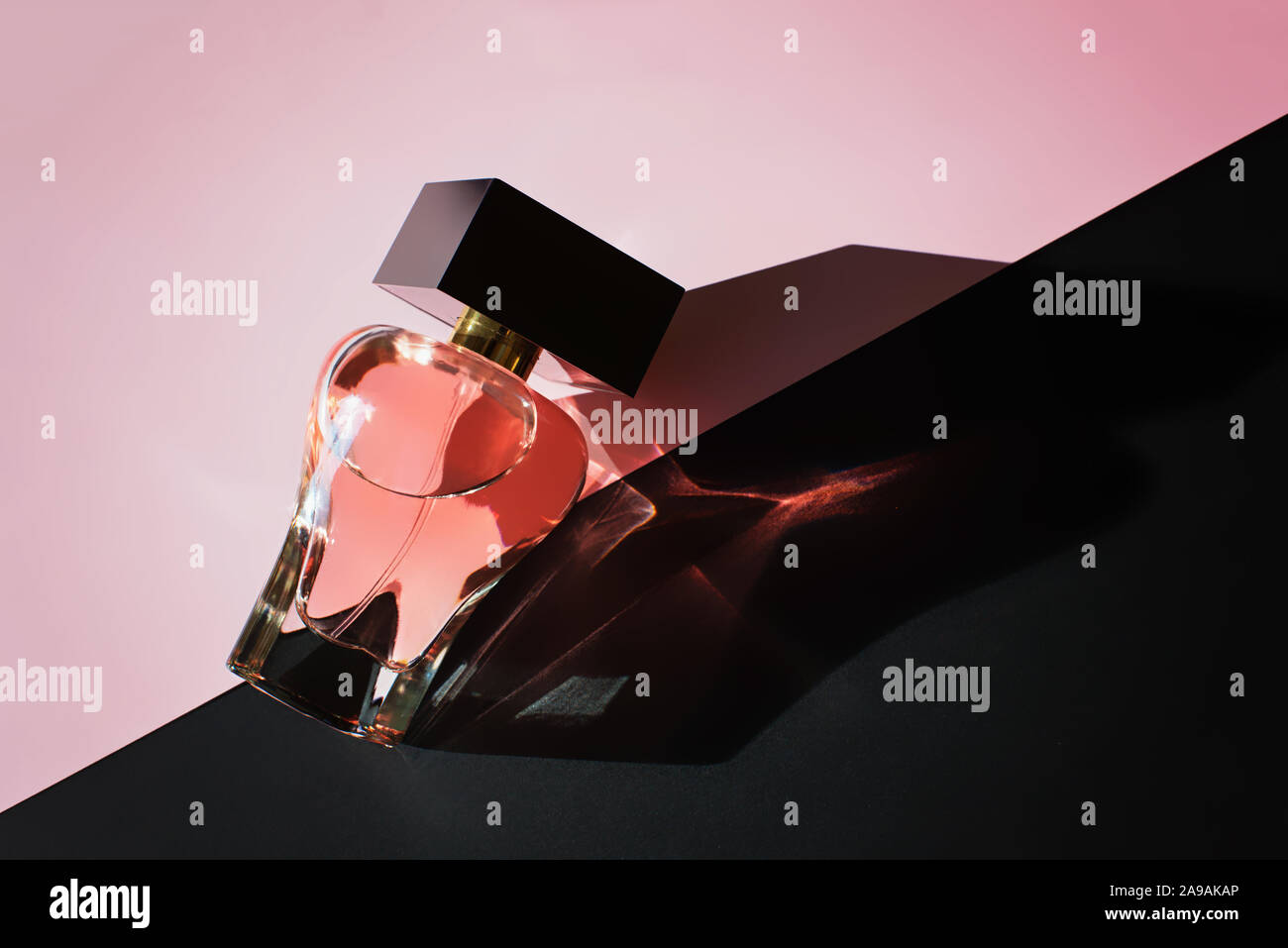 Bottle of perfume on pink and black background with contrast of light ...
