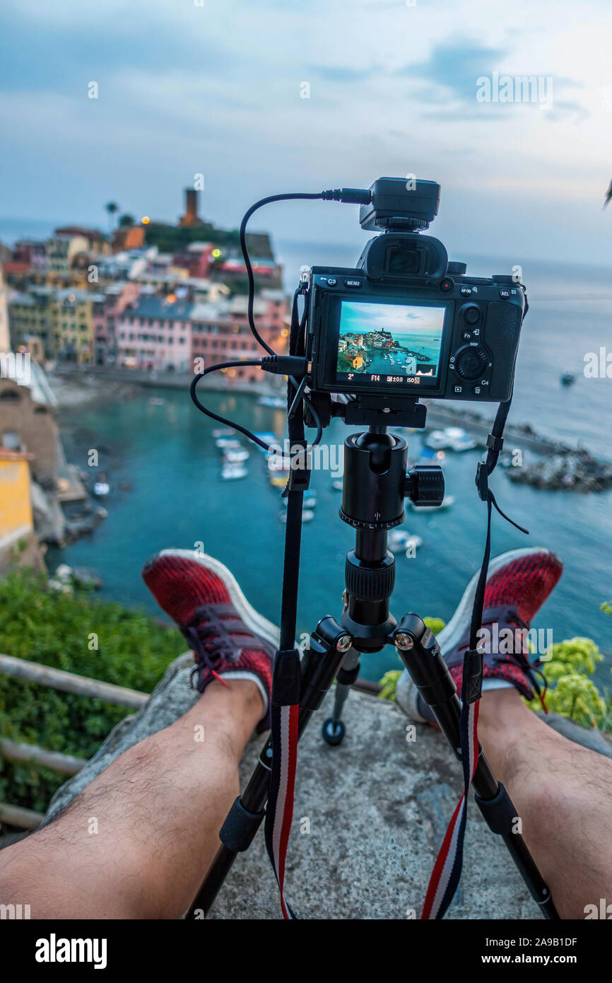Pro Camera on tripod on cliff capturing Vernazza city port at nightfall ...