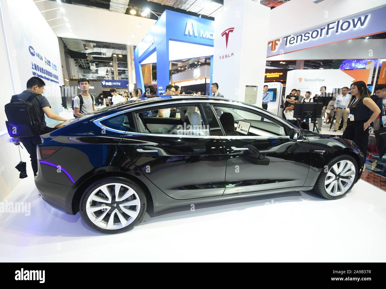 Visitors try out and view a Tesla Model 3 electric car on display ...