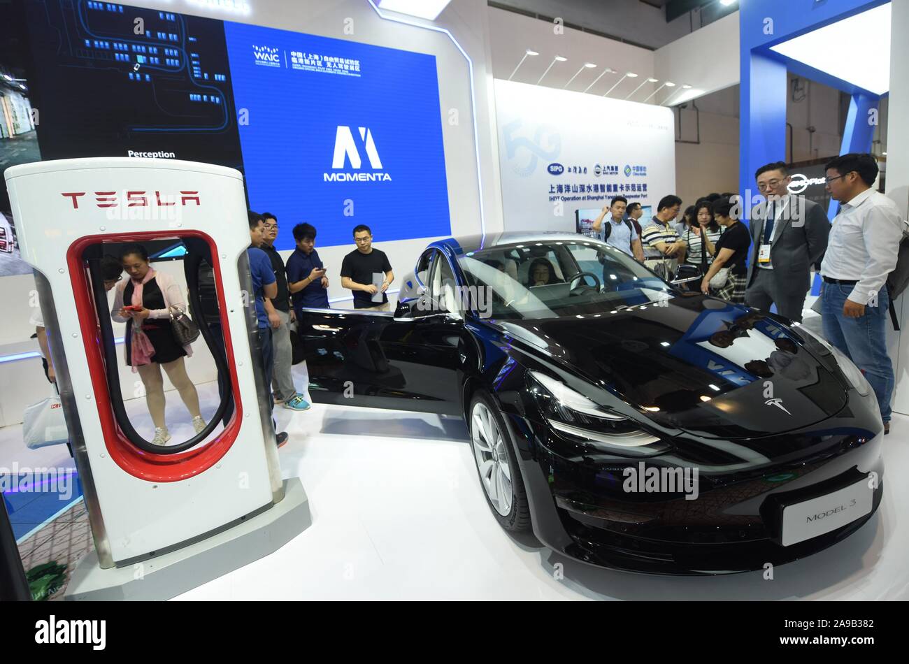 Visitors try out and view a Tesla Model 3 electric car on display ...