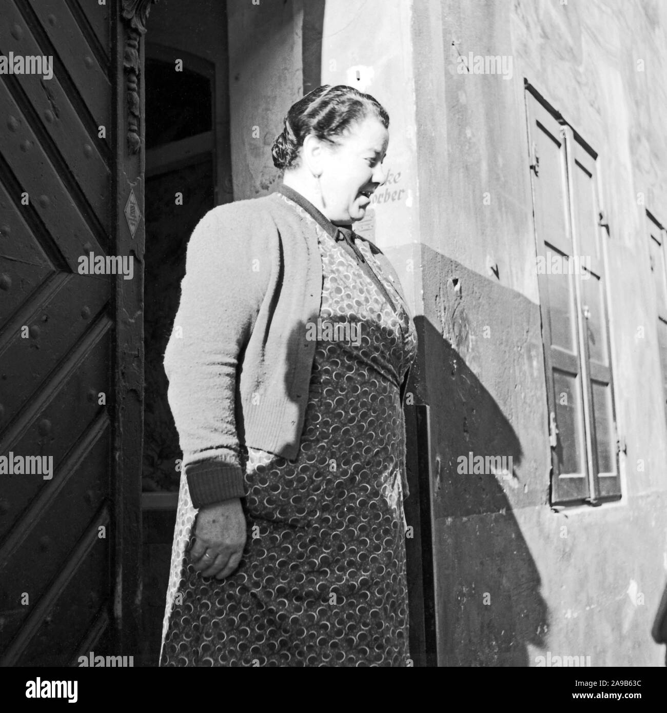 A housewife standing in front of then entrance to the house, Germany ...