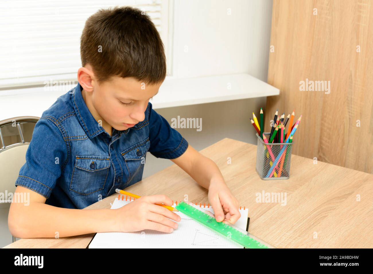 Boy draw in notebook. Child sitting at the desk home and doing his ...